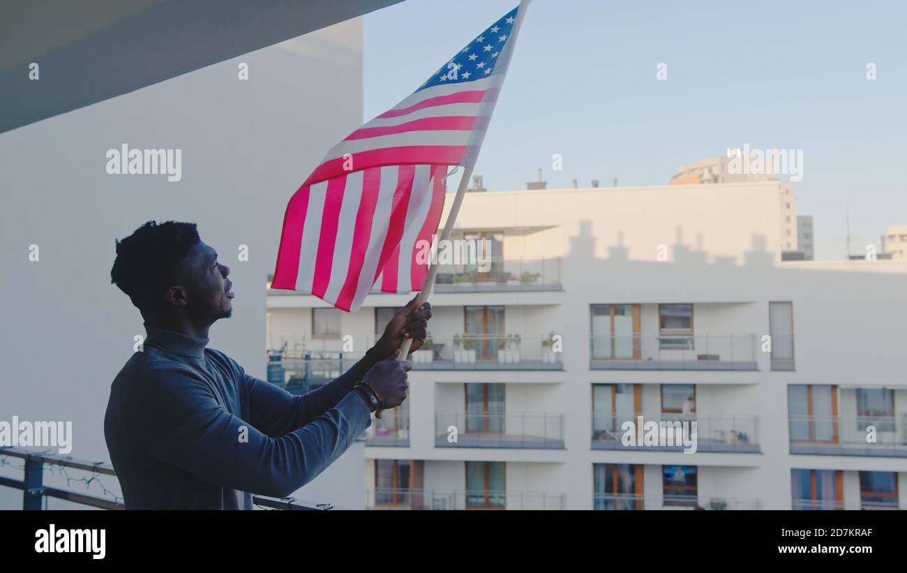 Young attractive black man waving American flag from the balcony. High ...