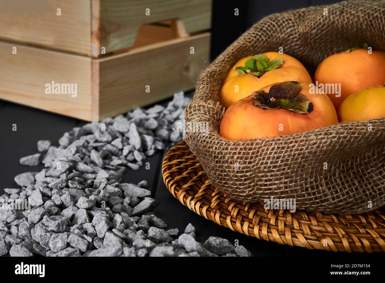 sack of delicious persimmons on a wicker plate, a vintage wooden box ...