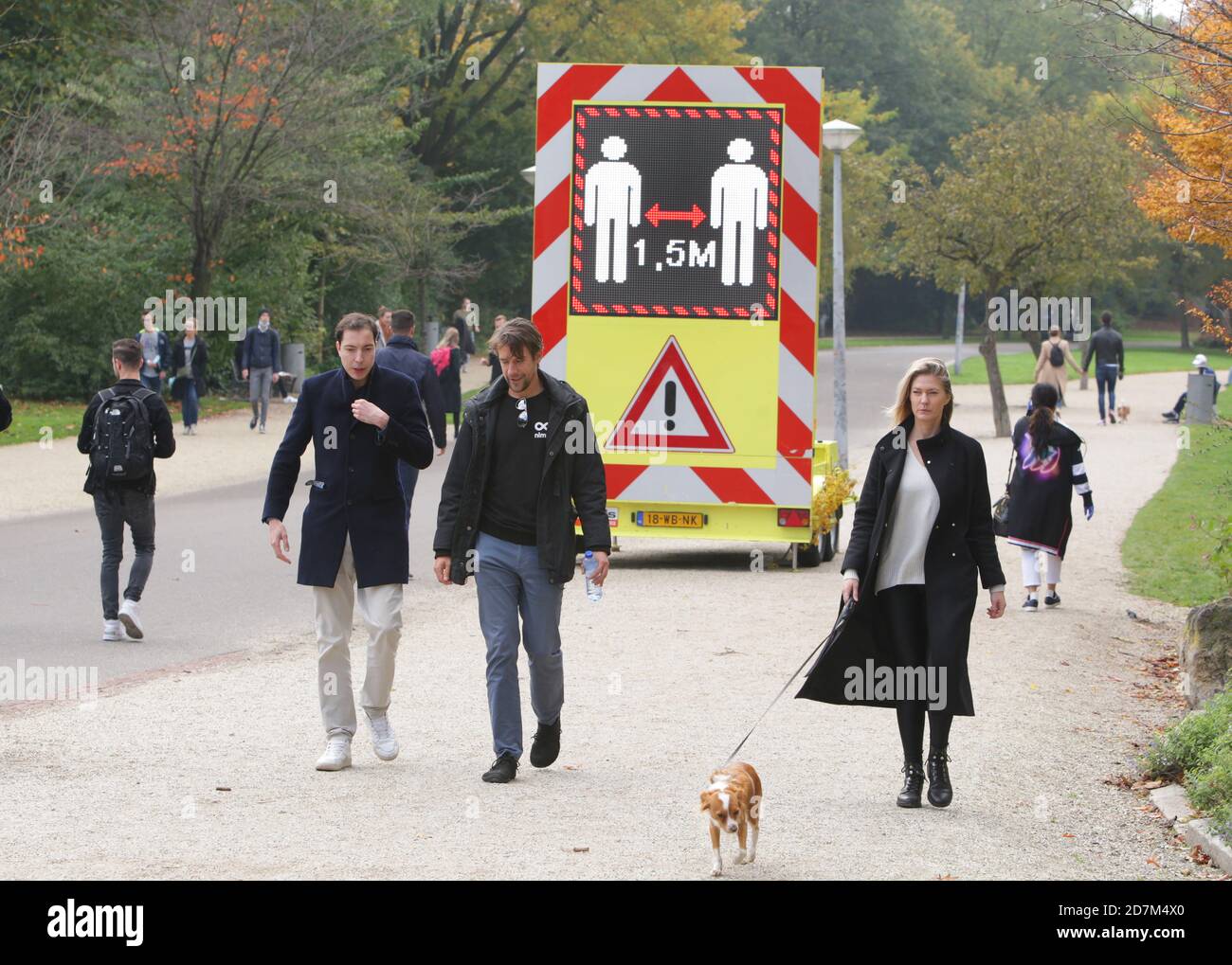 People walks past near a electronic sign urging people to practice ...