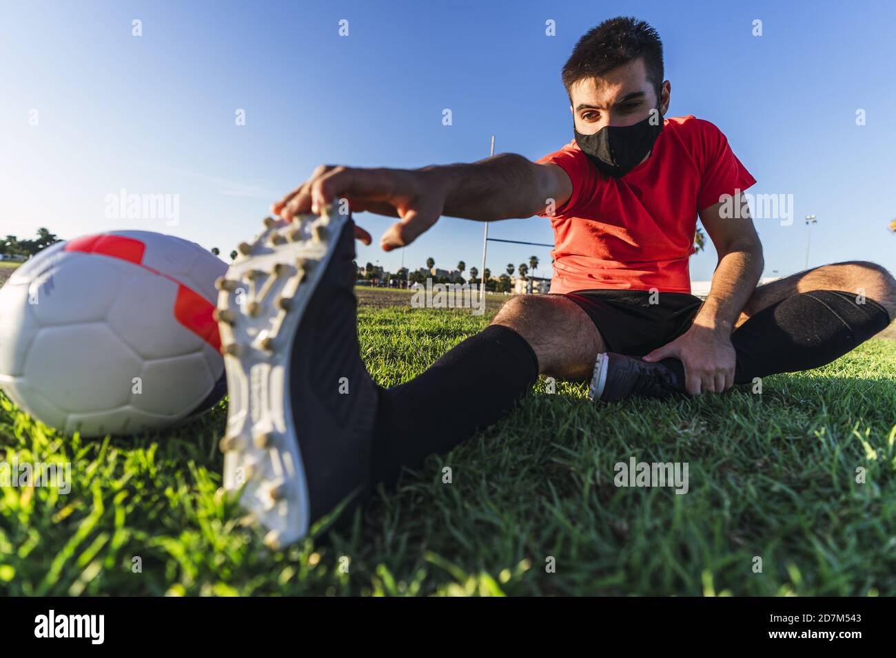 Young European male footballer stretching in a black mask Stock Photo ...