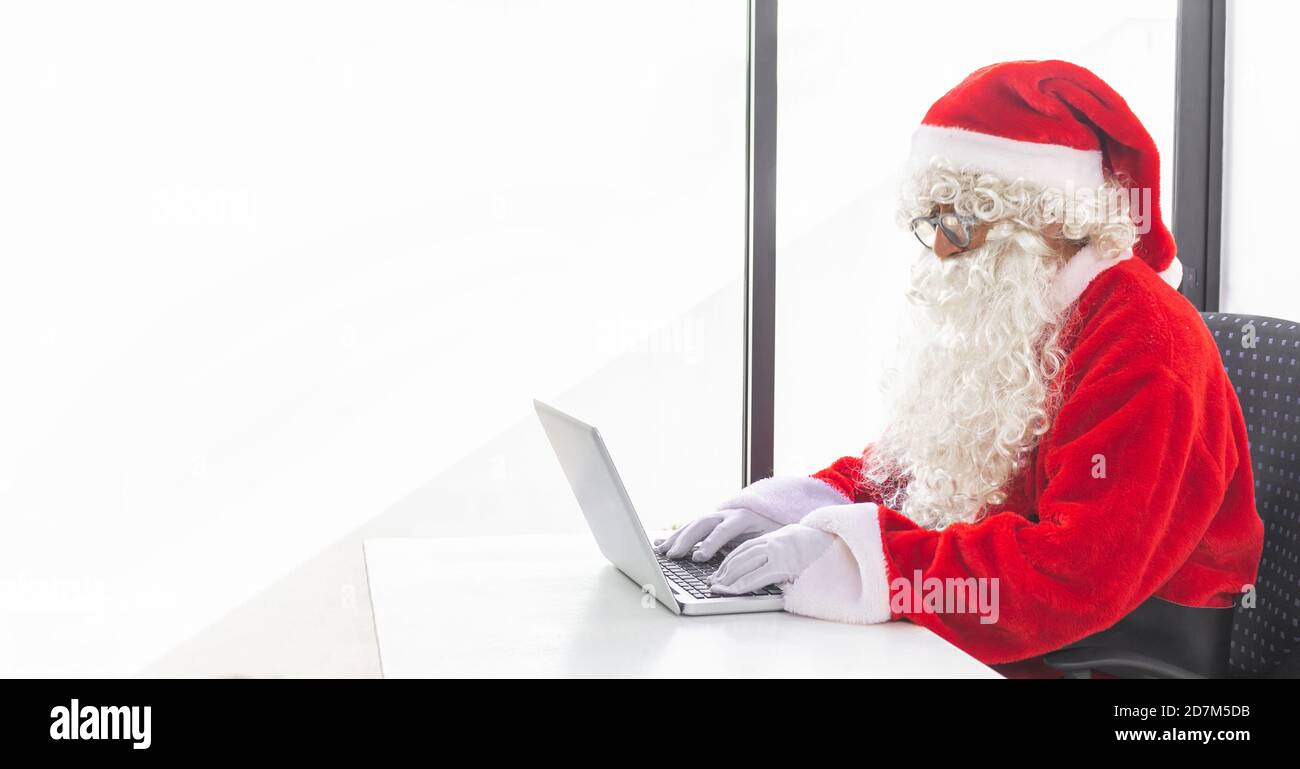 Santa Claus working on a laptop in a minimalist white office at ...