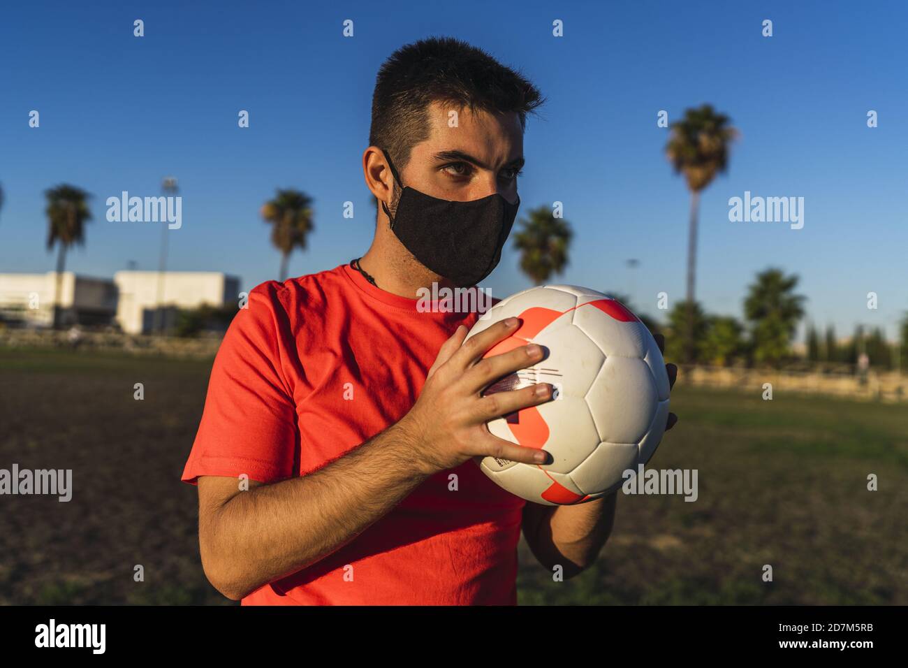 Soccer player in a black mask holding a ball Stock Photo - Alamy
