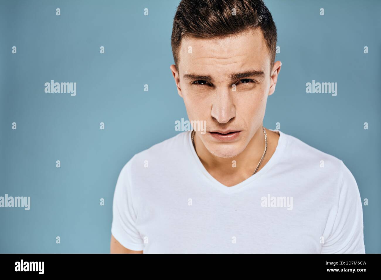 emotional displeased man cropped view white t-shirt blue background ...