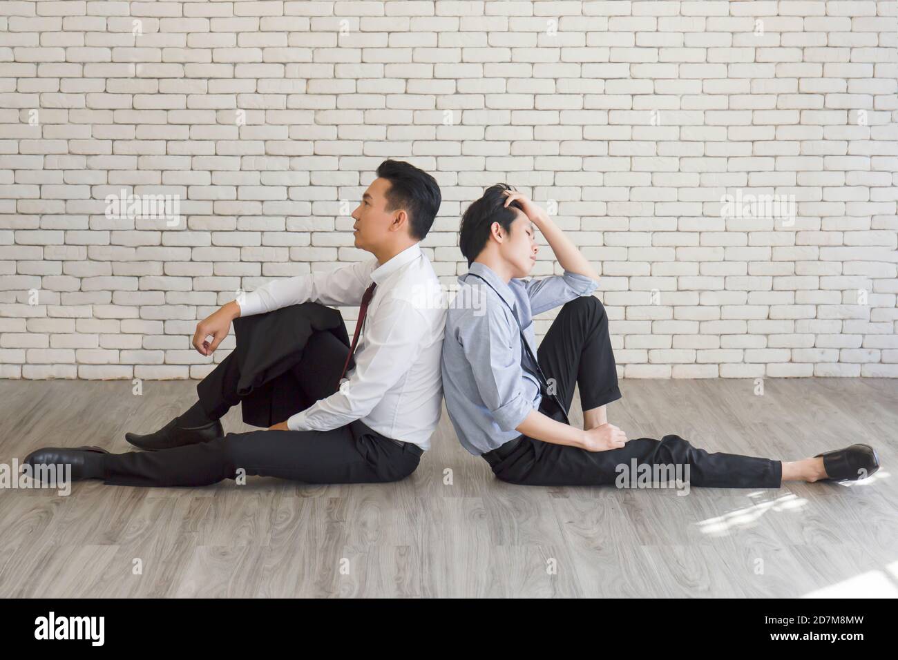 Two male employees sat on the floor showing signs of stress from ...