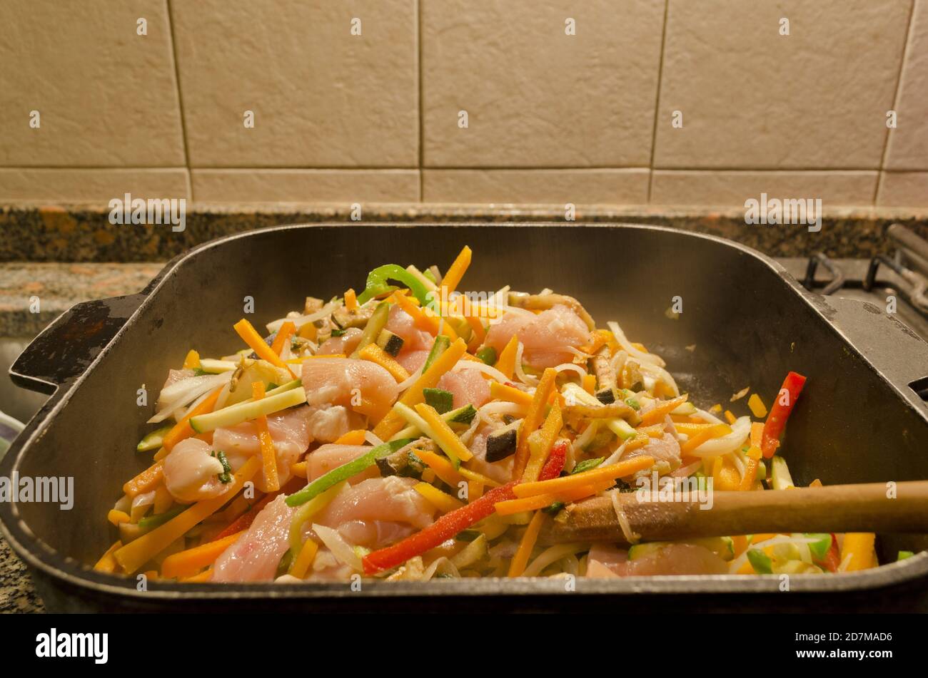 Dish with chicken and sliced vegetables being prepared in a kitchen ...