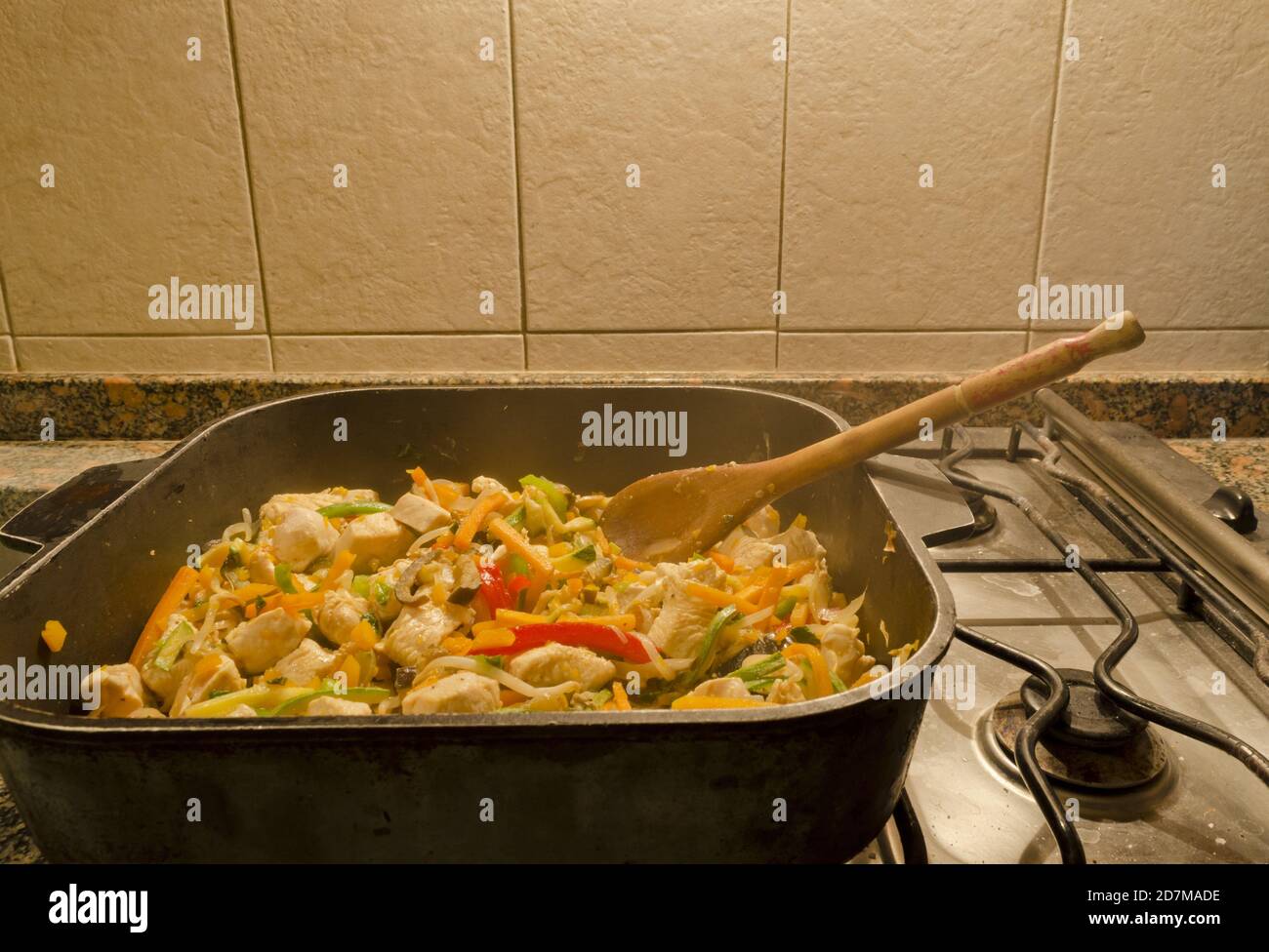 Dish with chicken and sliced vegetables being prepared in a kitchen ...