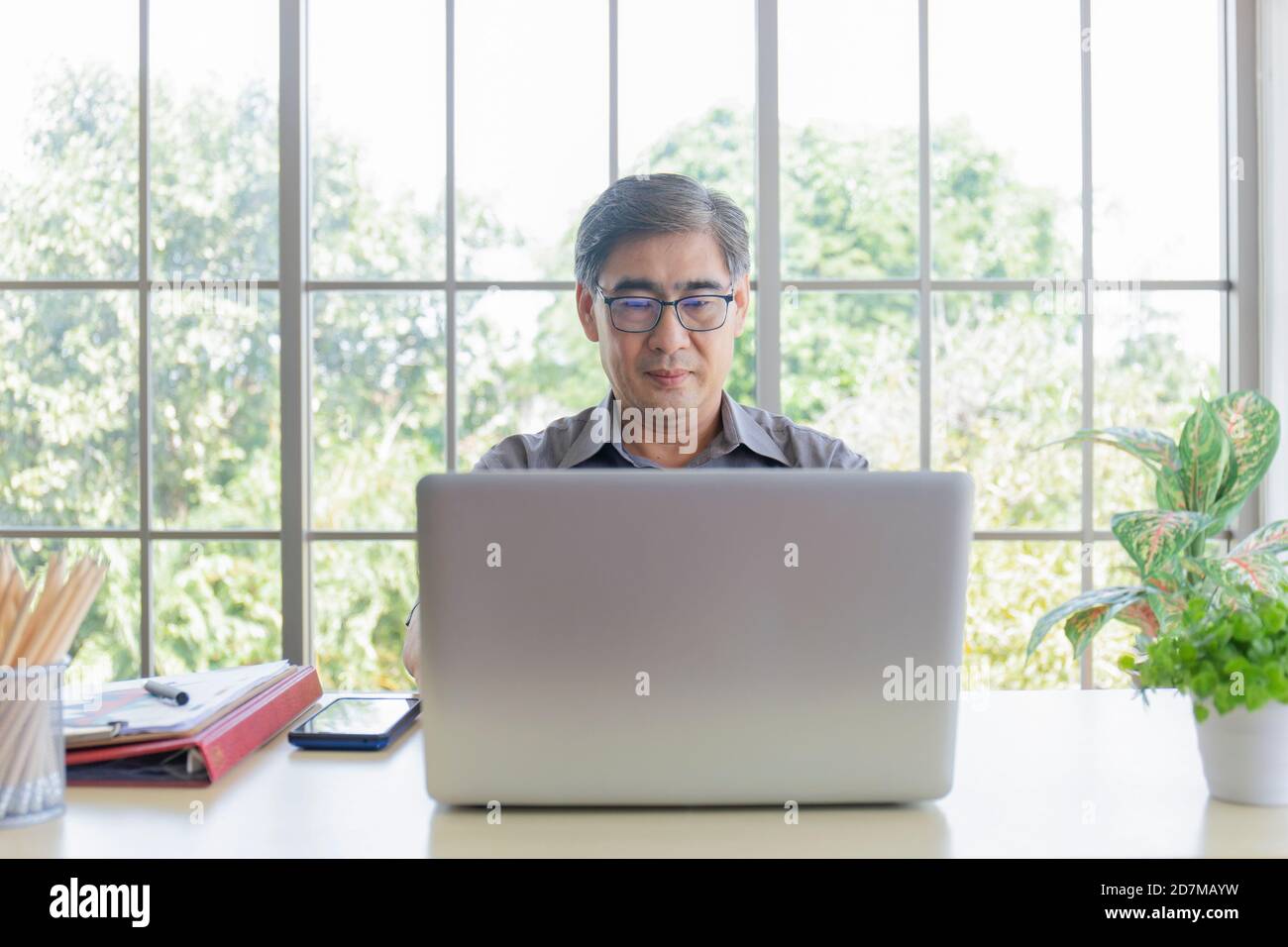 An elderly Asian man is learning how to trade online with a laptop on ...