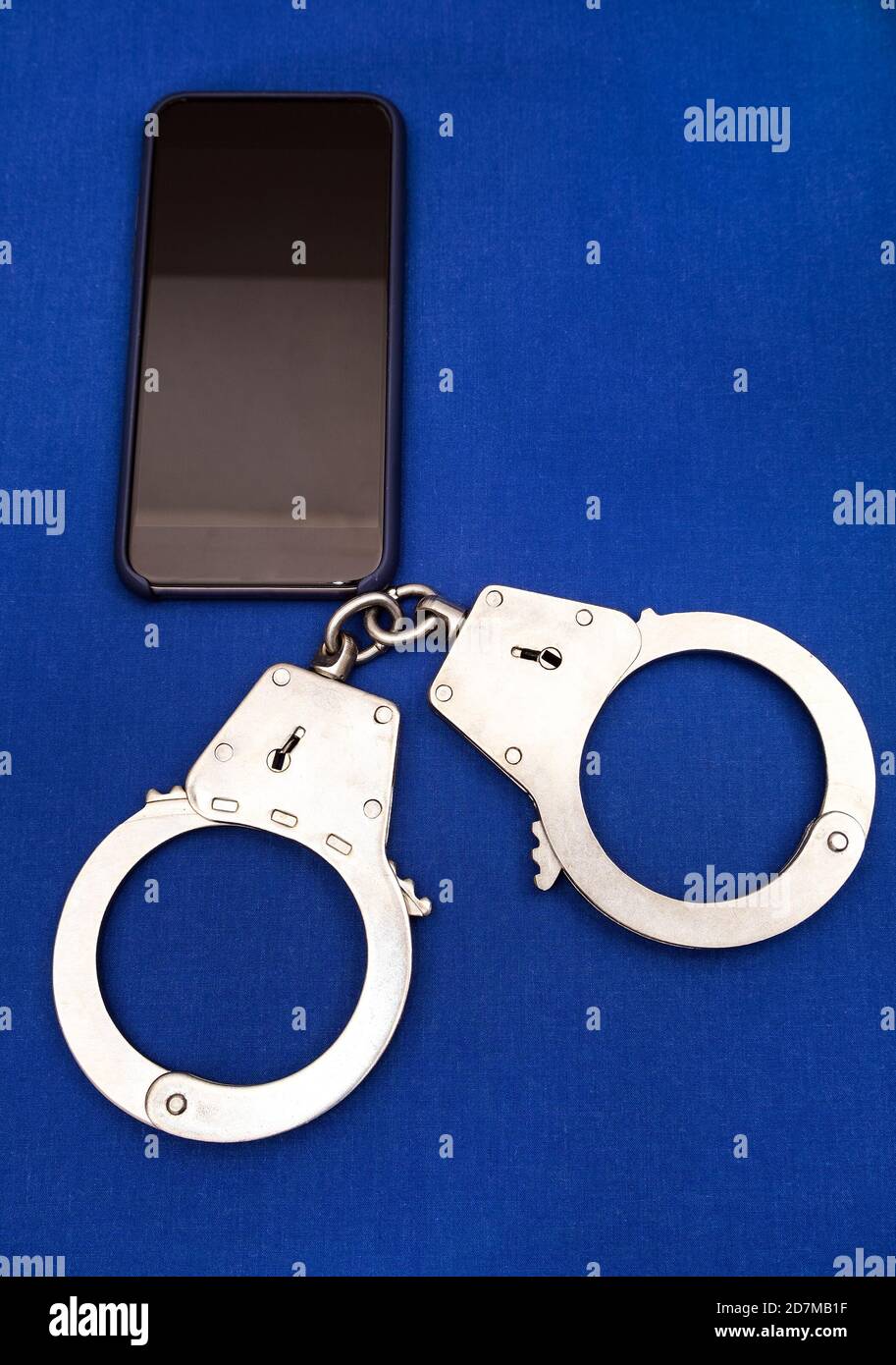 Handcuffs and Mobile Phone on the Blue Paper Background Stock Photo - Alamy