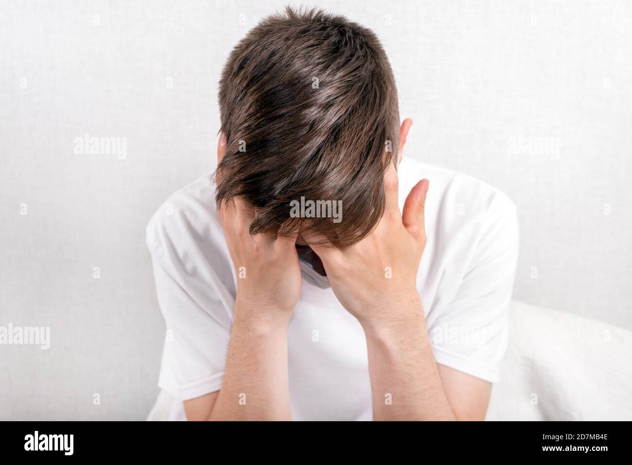 Sad Young Man by the White Wall closeup Stock Photo - Alamy