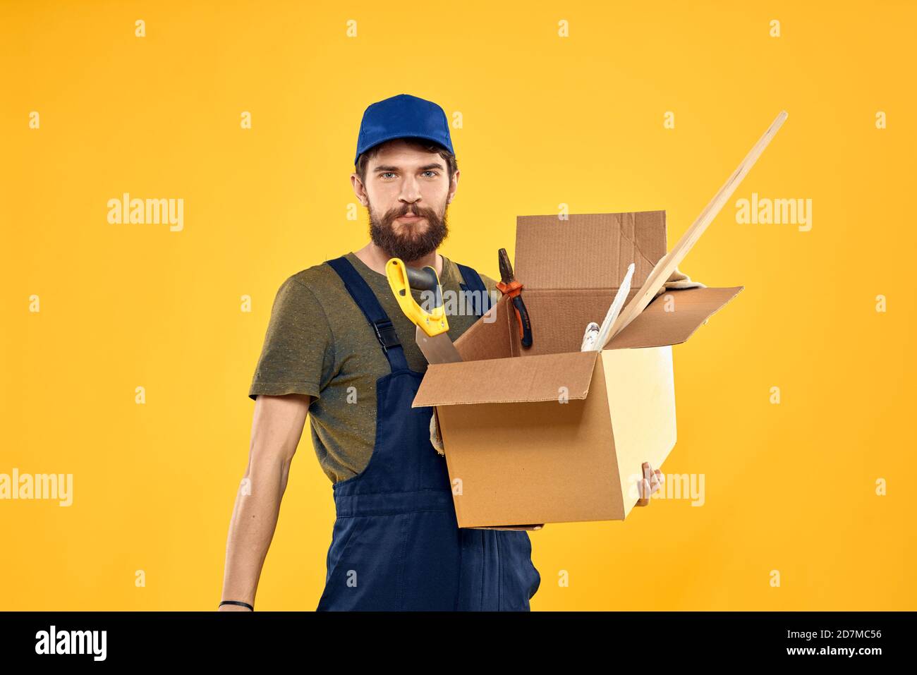 A man in a working form a box with loading tools yellow background ...