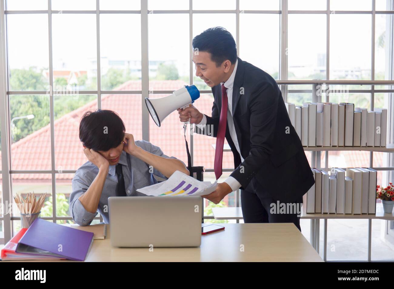 An angry Asian man manager shouting in a loudspeaker in his subordinate ...