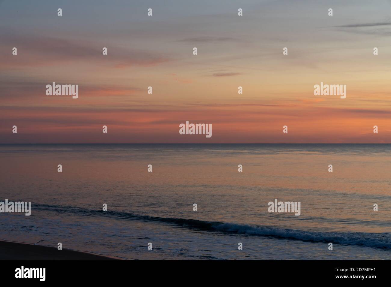 A beautiful sunset over the ocean with colorful sky and small waves ...