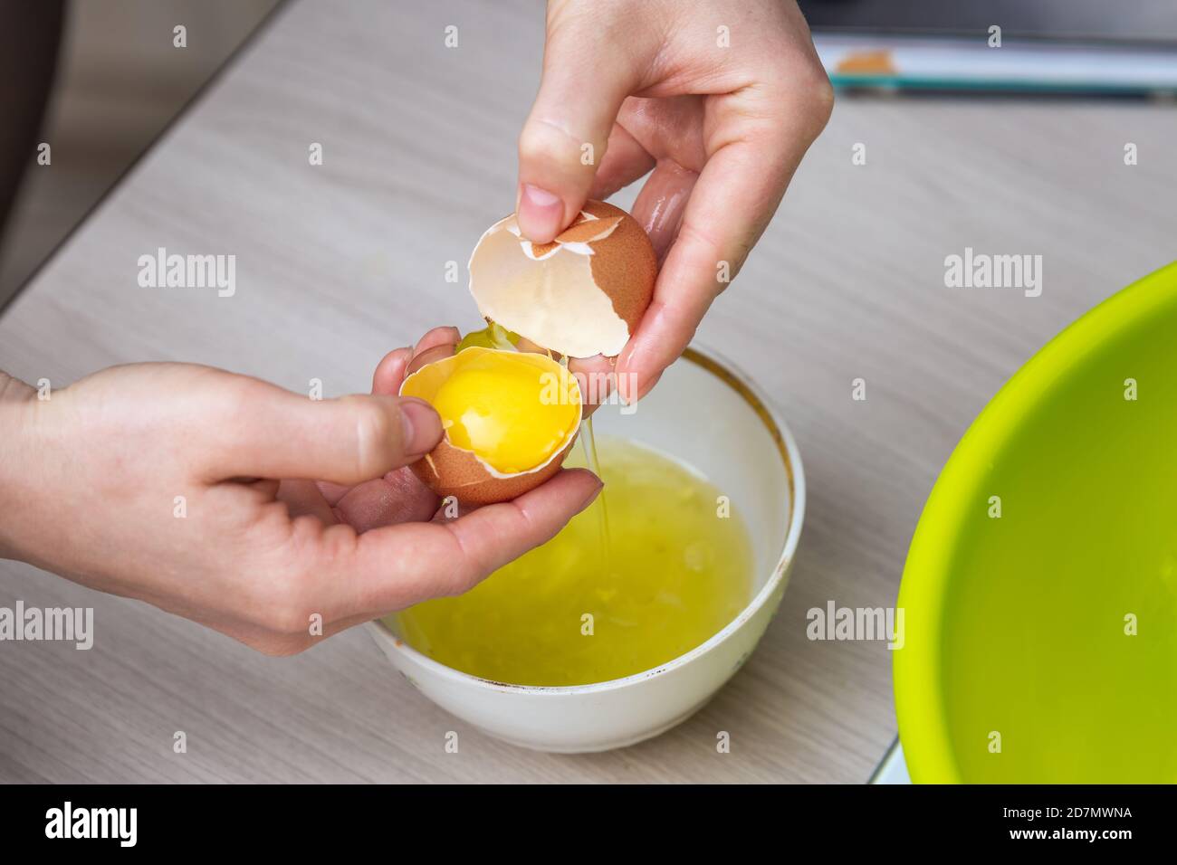 Close-up woman's hands break the egg and separate the white from the ...
