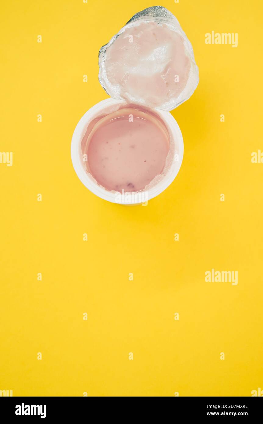 Vertical shot of an opened plastic container of fruit yogurt on a ...