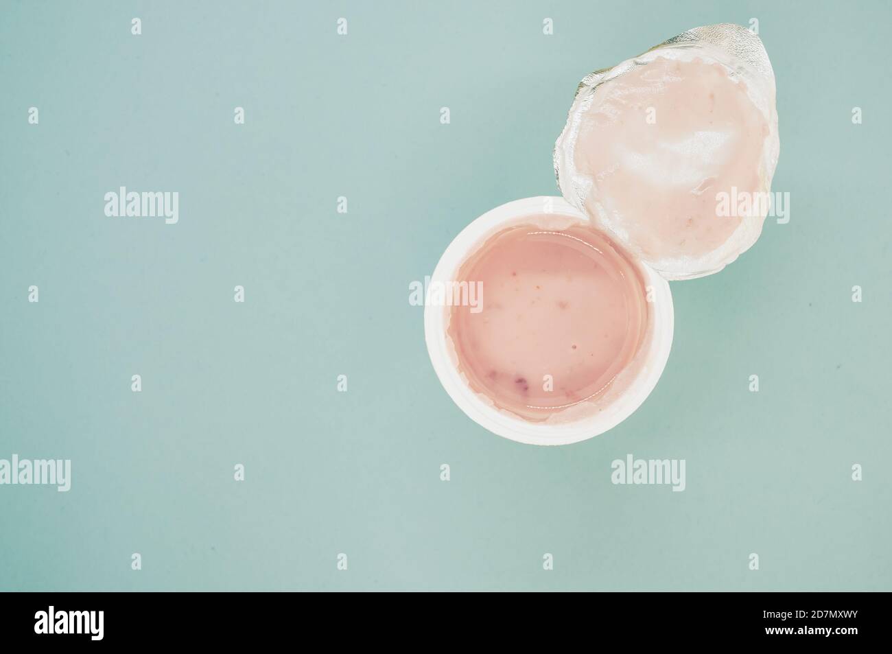 Top view of an opened plastic container of fruit yogurt on a blue ...