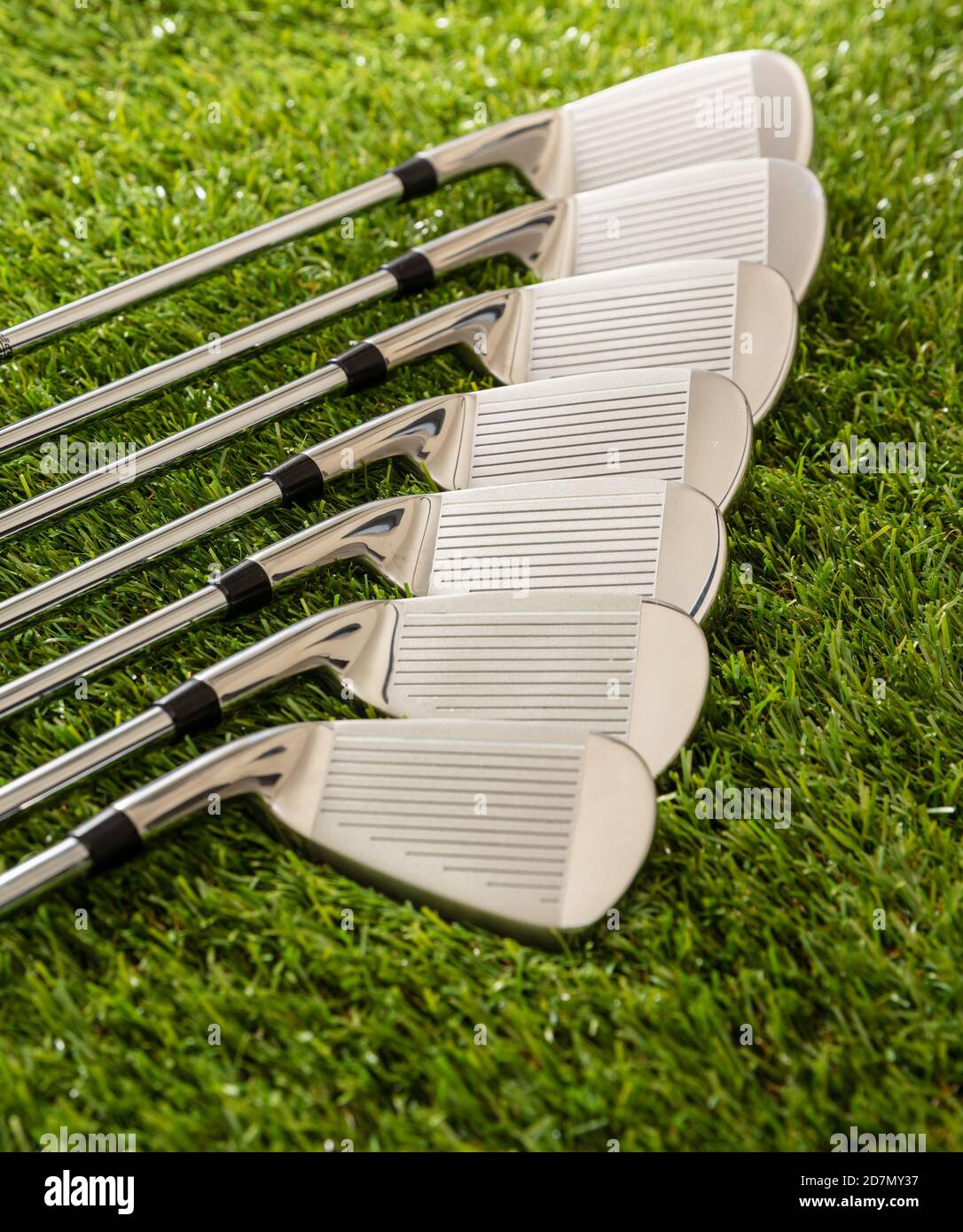 Golf sticks set on green course lawn, sunlight reflections, close up ...