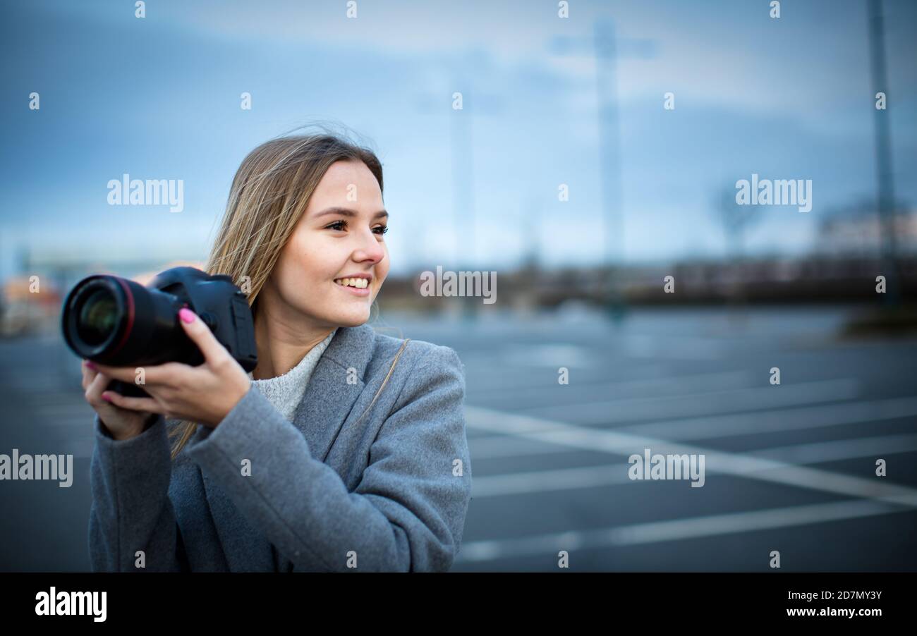 Pretty, young woman taking photos with her professional dslr camera ...