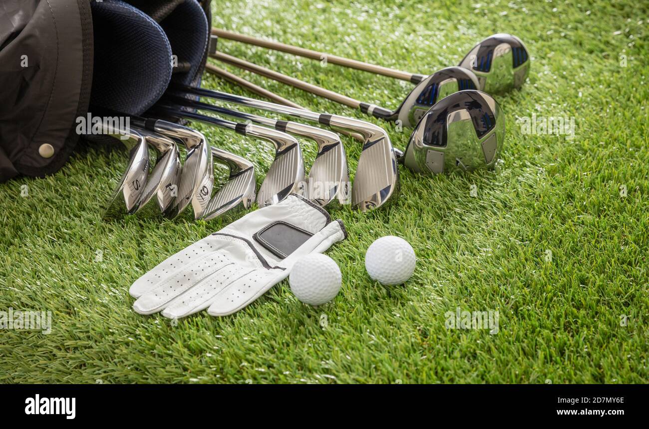 Golf equipment, sticks set in a bag glove and golfballs on green course ...