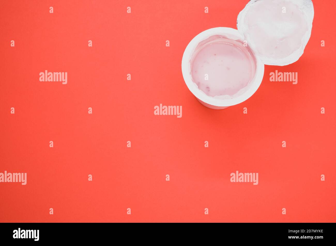 Top view of an opened plastic container of fruit yogurt, on a red ...