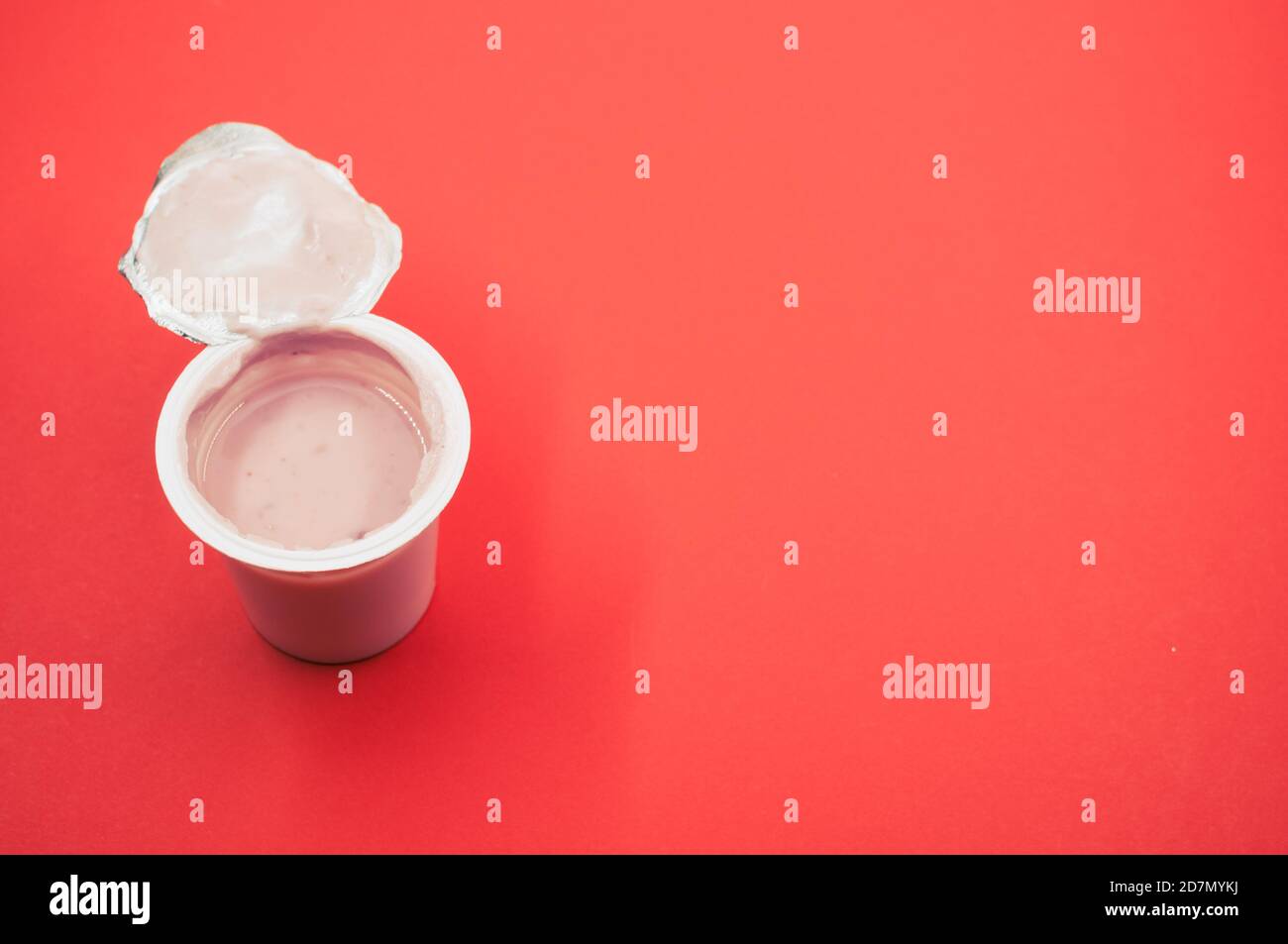 High angle shot of an opened plastic container of fruit yogurt, on a ...