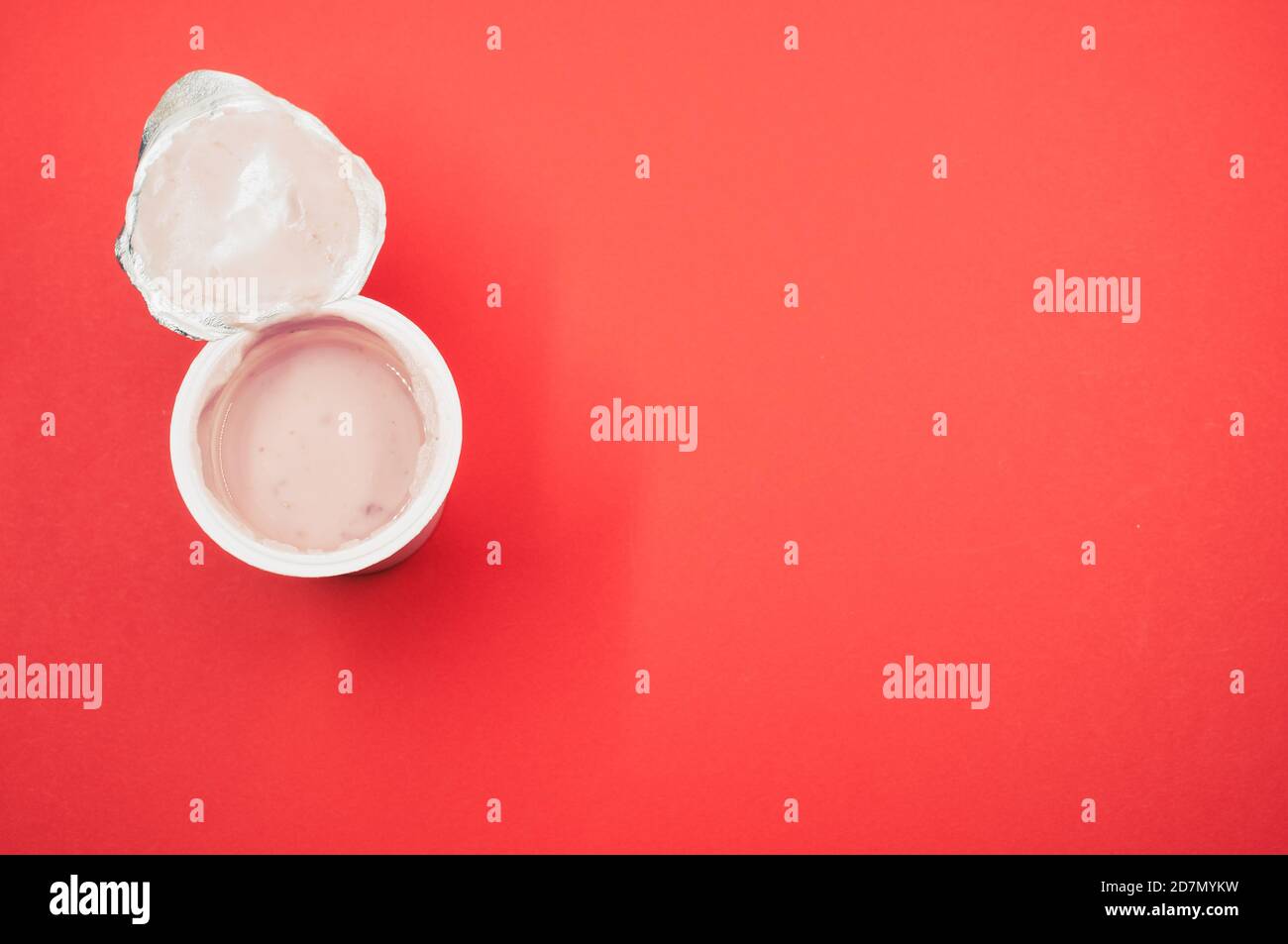Top view of an opened plastic container of fruit yogurt, on a red ...