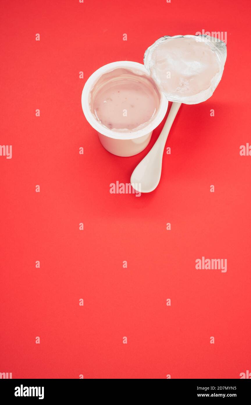 Vertical shot of an opened plastic container of fruit yogurt and a ...