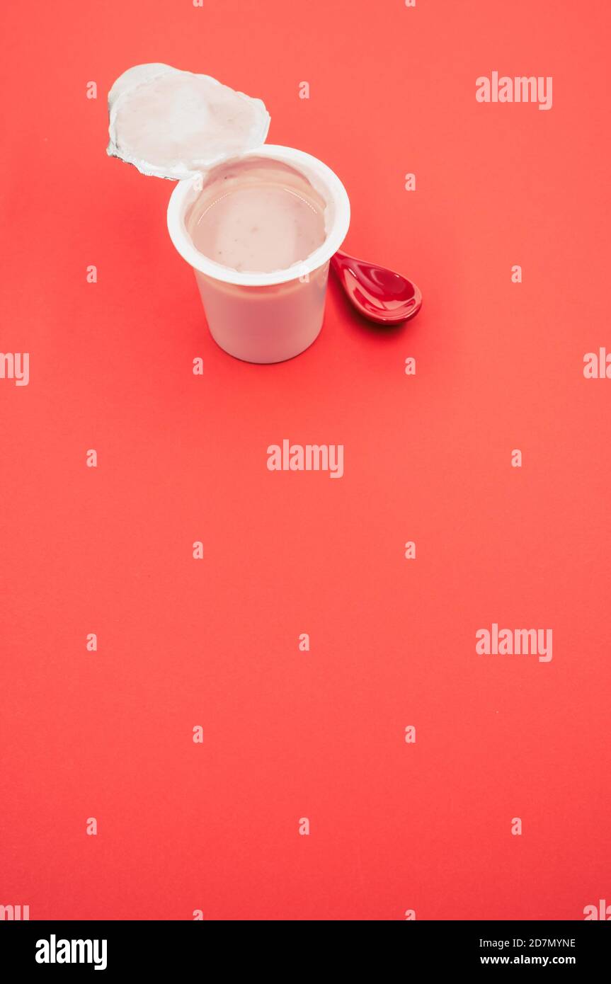 Vertical shot of an opened plastic container of fruit yogurt and a ...