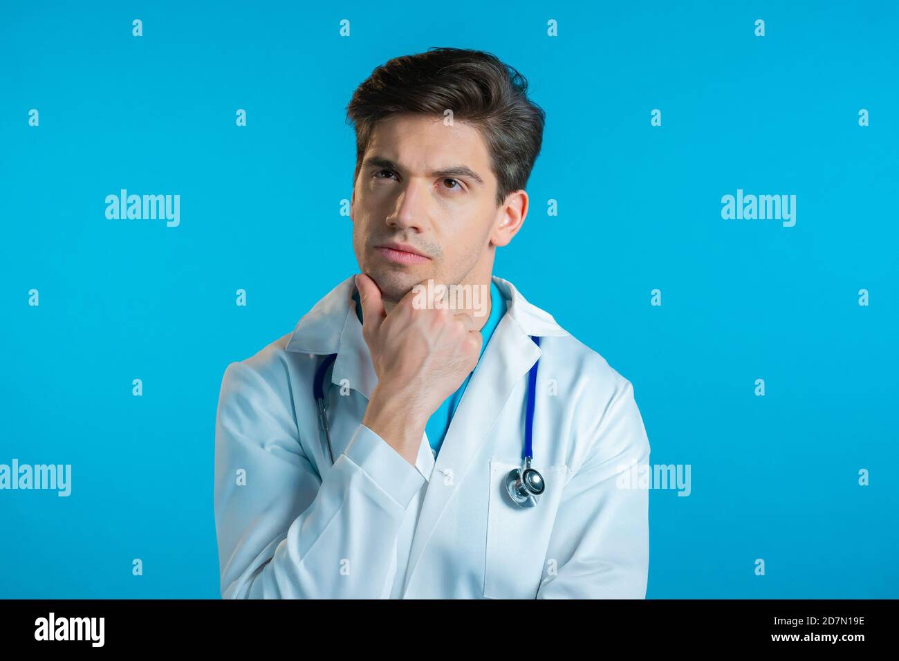 Thinking doctor man looking up and around on blue background. Worried ...