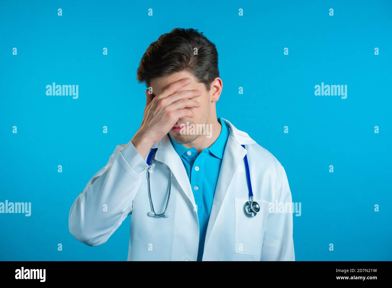Frustrated doctor man in white wear over blue wall background. Doc is ...