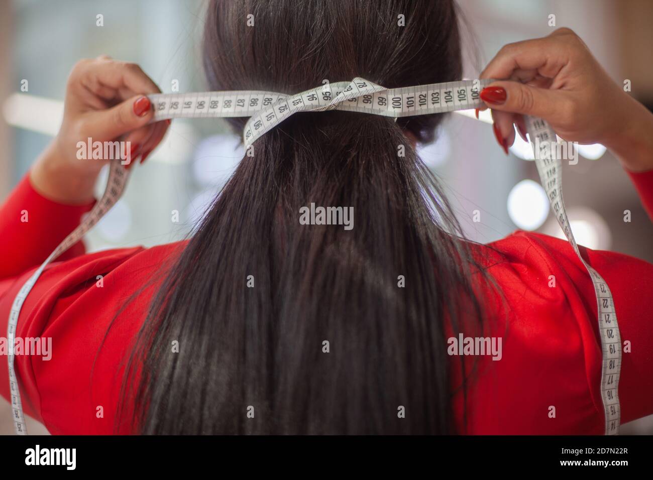 Female fashion designer in red dress wrapped her hair with tape measure ...