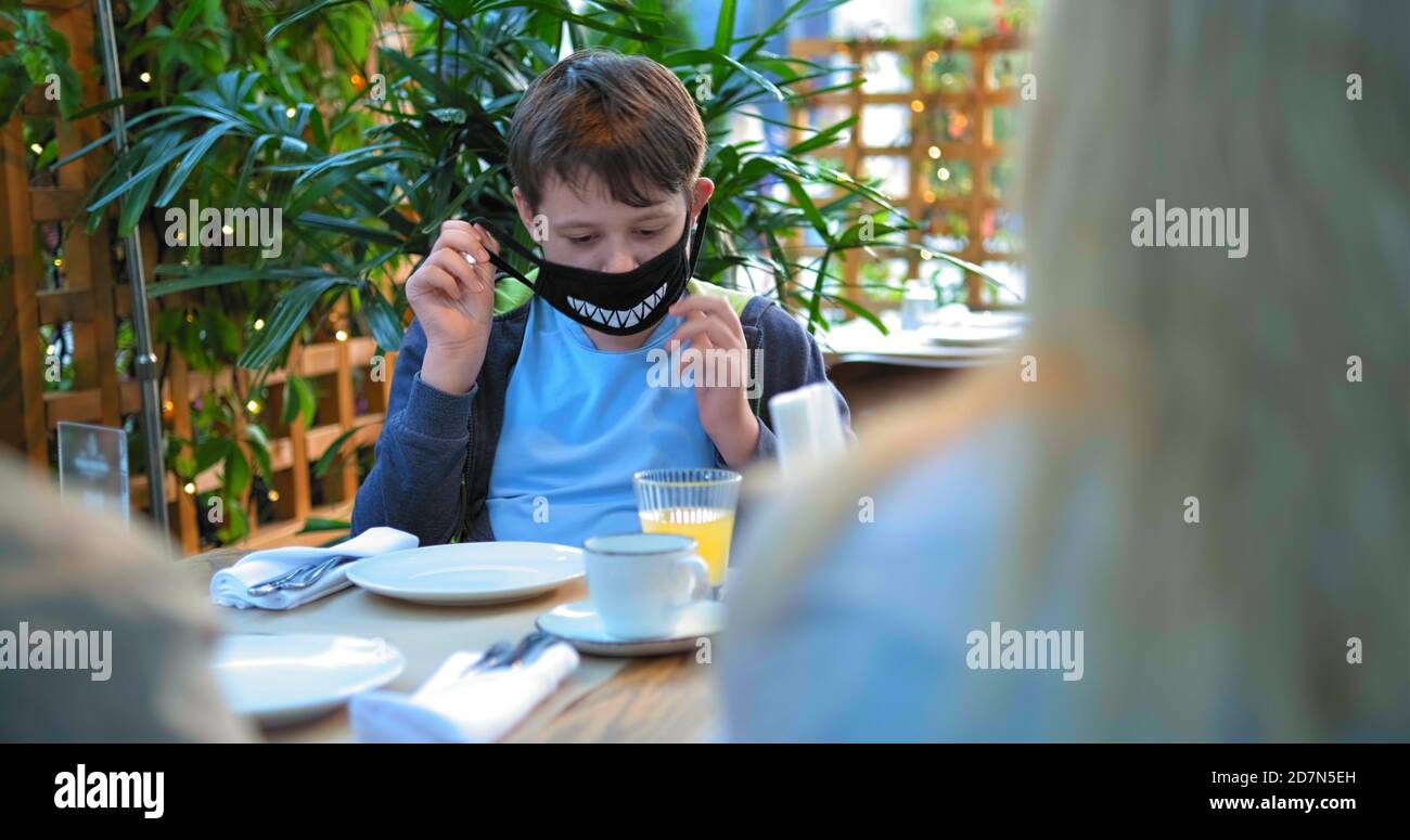 schoolboy takes face mask off and drinks juice from glass sitting at ...