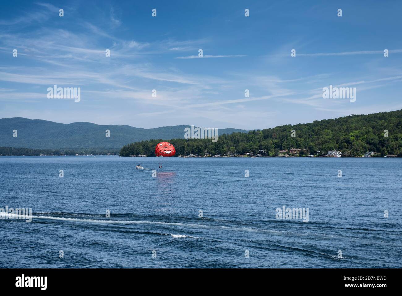 a speedboat pulling a parasail on lake george on a sunny blue sky ...