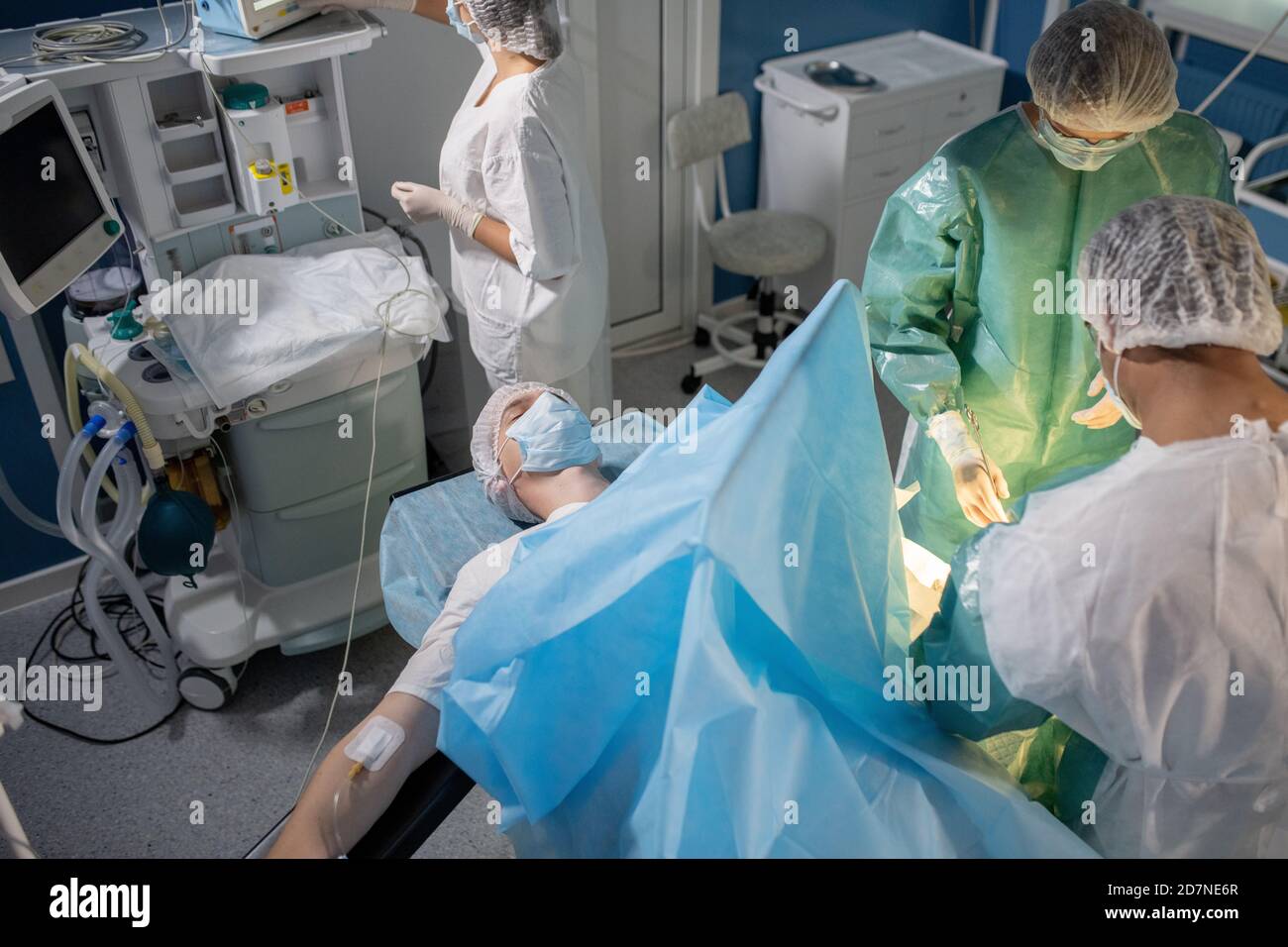 Patient lying on operation table while professional surgeons bending ...