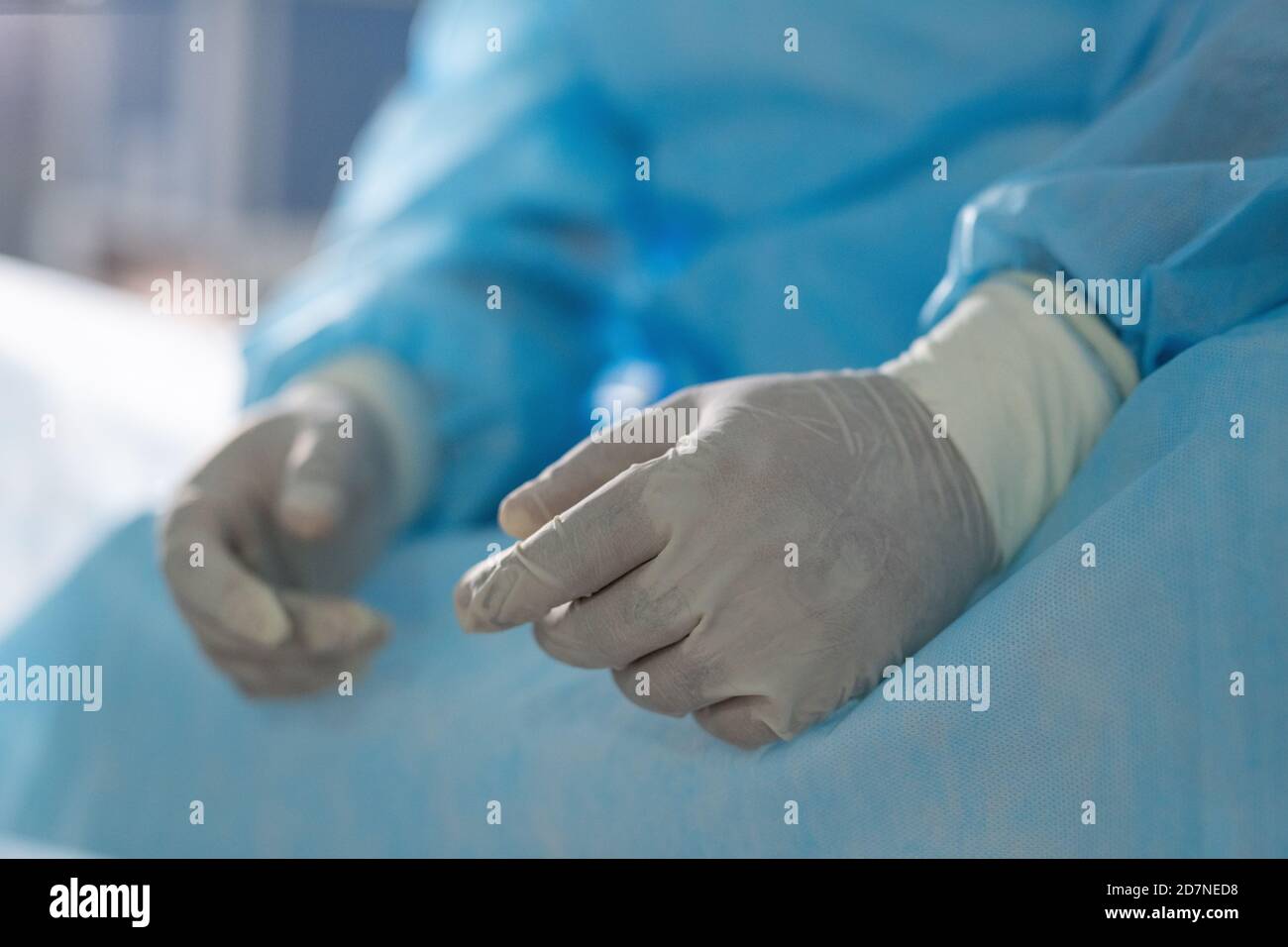 Gloved hands of tired professional surgeon sitting in operating room at ...