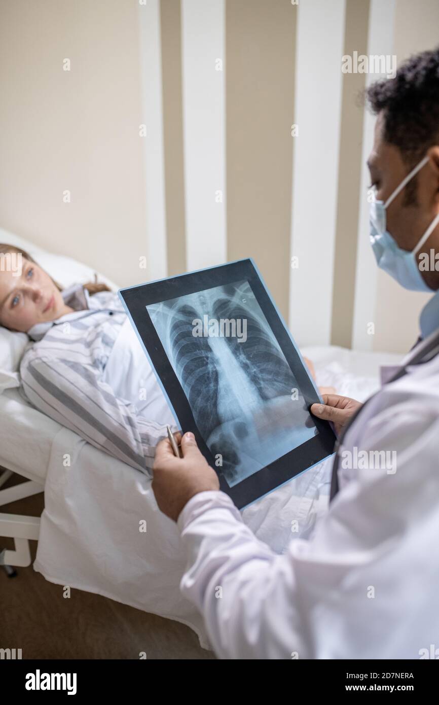 Male radiologist looking at lung x-ray image of sick female patient ...
