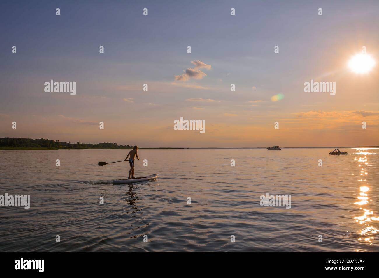 Young boy rowing on a sup in the sunset Stock Photo - Alamy