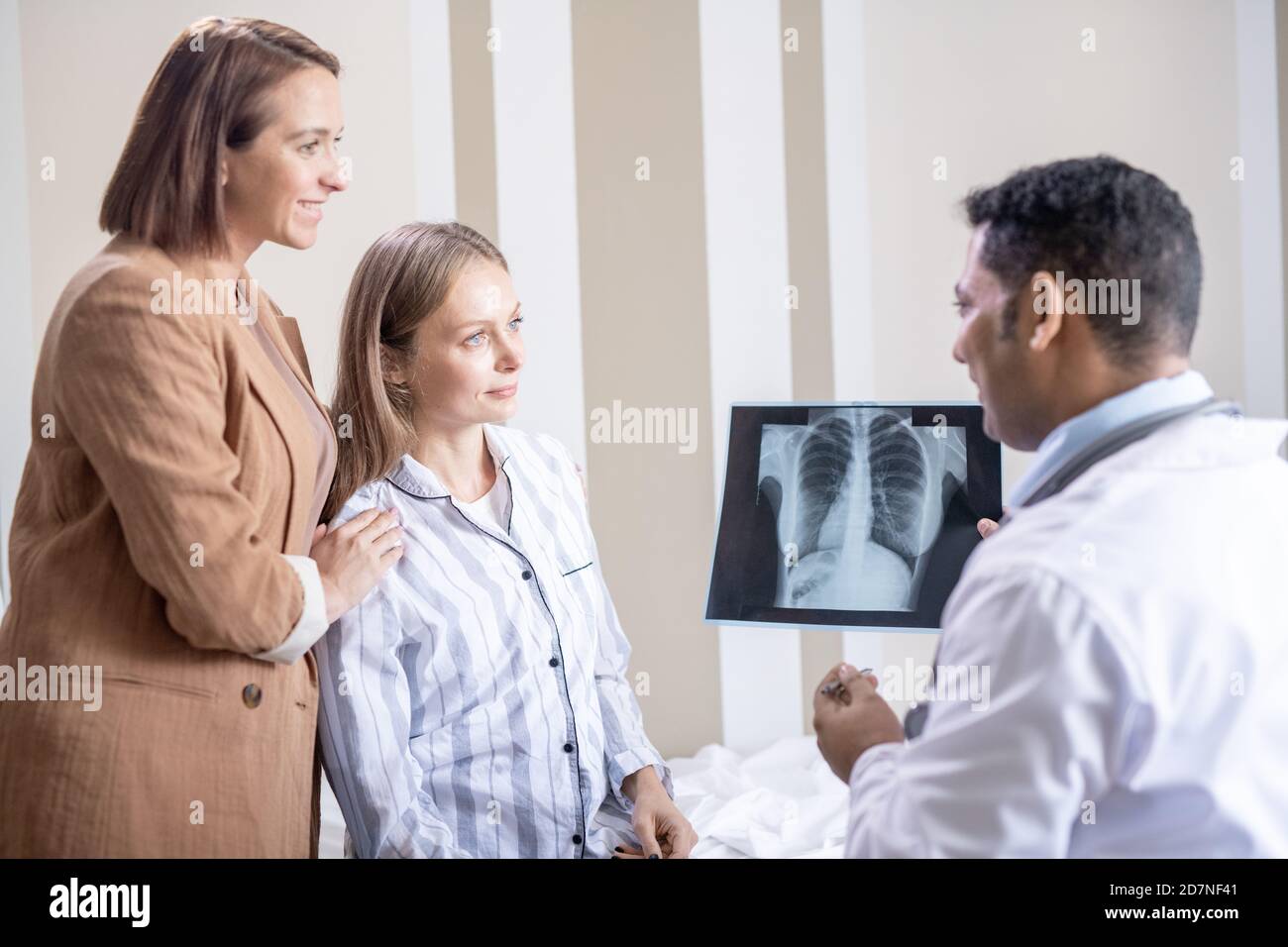 Confident radiologist with lung x-ray looking at his patient and her ...