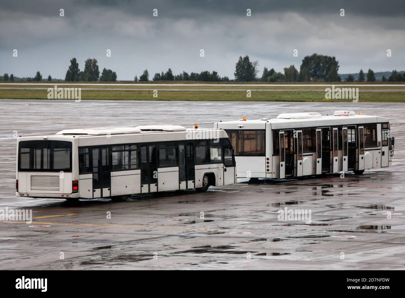 Two empty shuttle buses at the airport apron in a rainy day Stock Photo ...