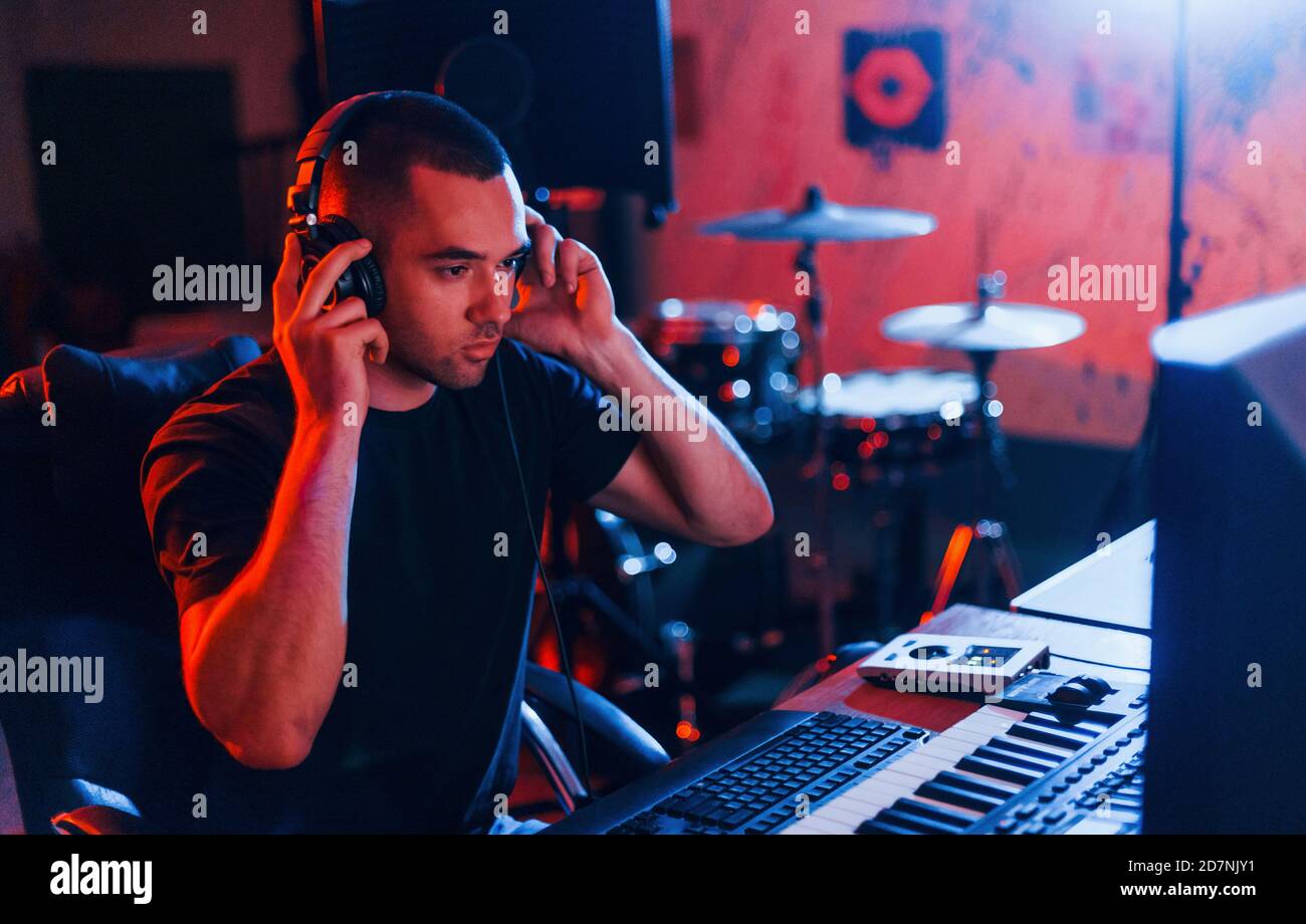 Sound engineer in headphones working and mixing music indoors in the ...