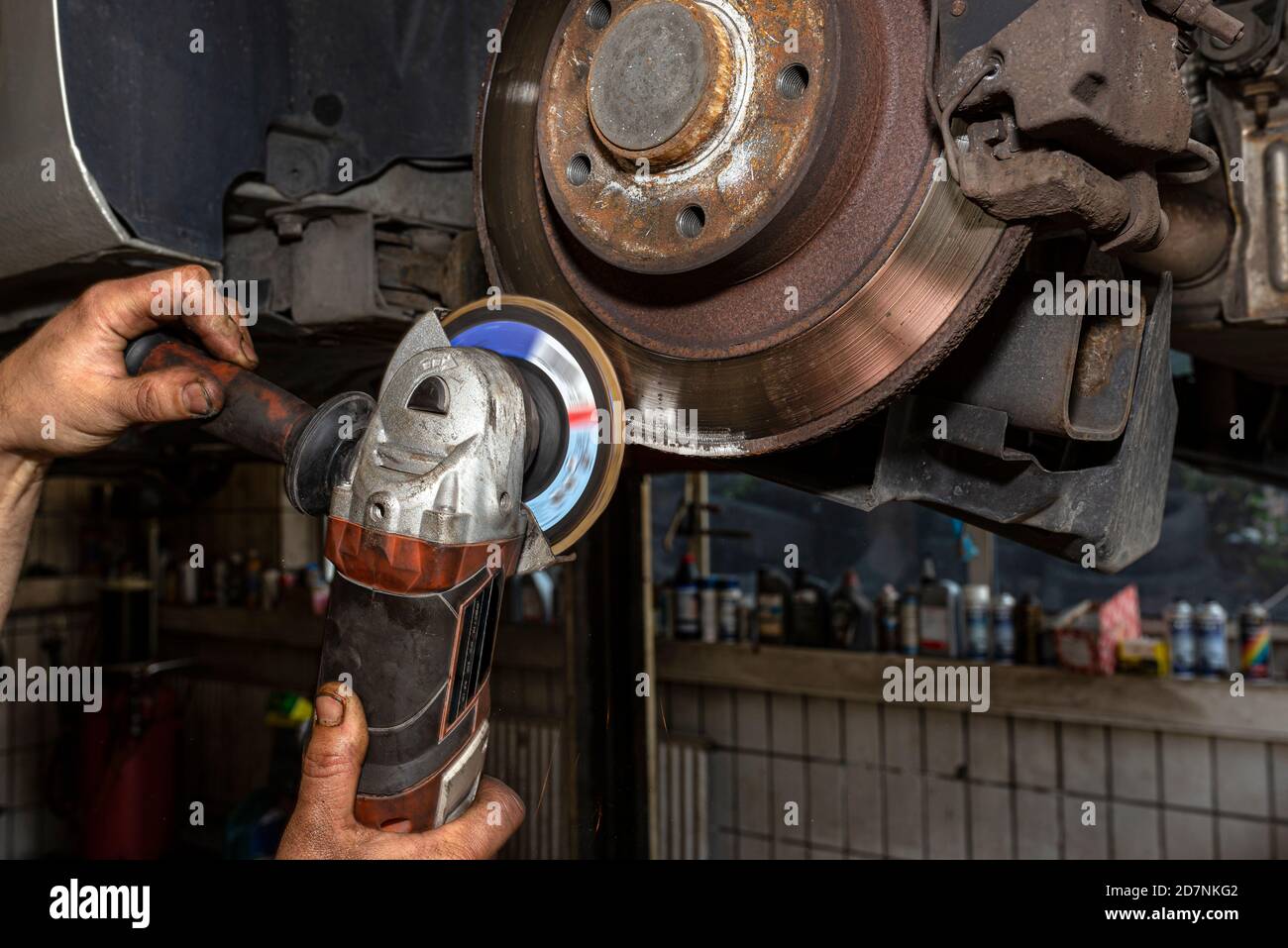 A mechanic grinds, with an angle grinder, the edge of an old rear brake ...