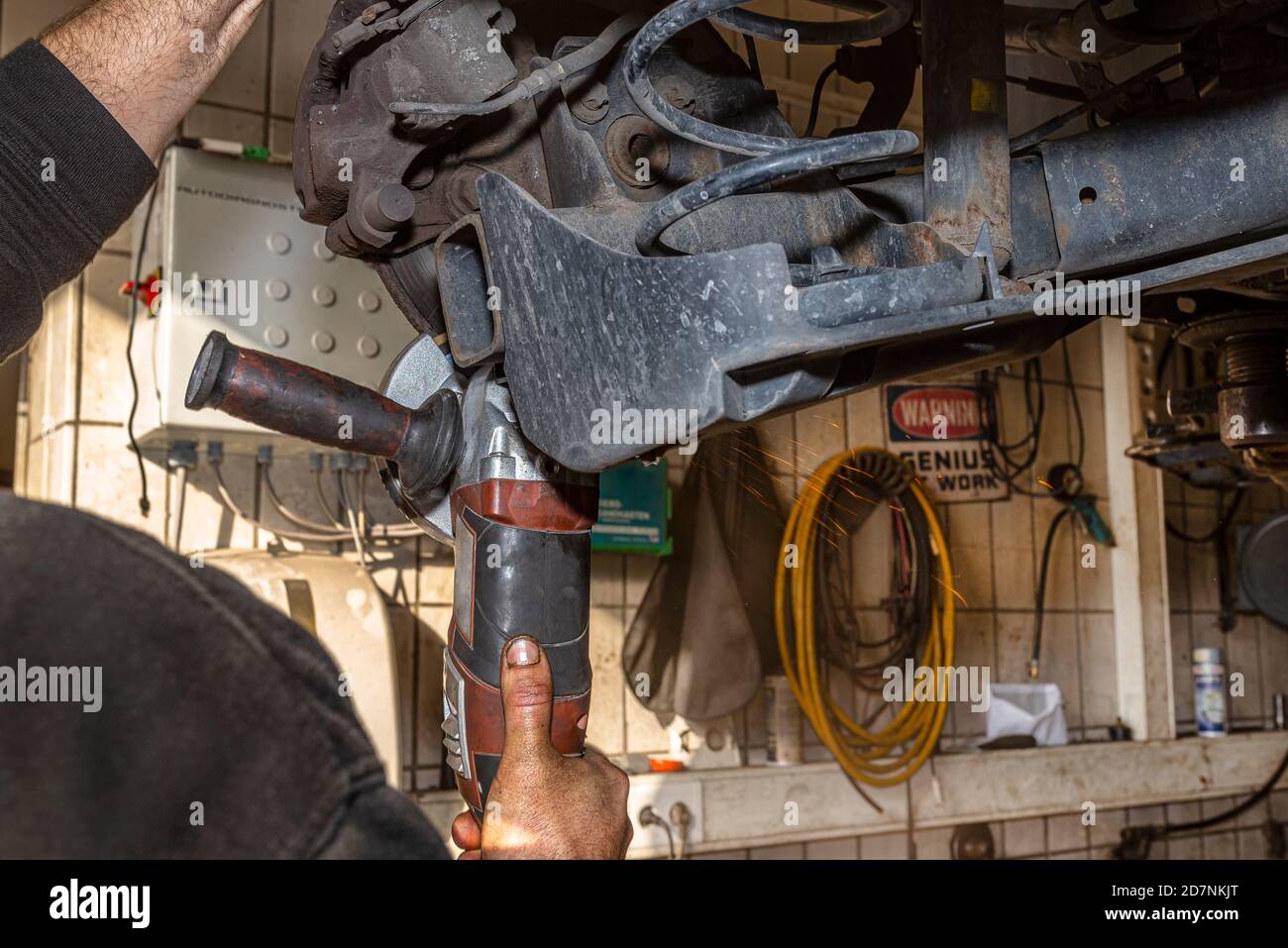 A mechanic grinds, with an angle grinder, the edge of an old rear brake ...