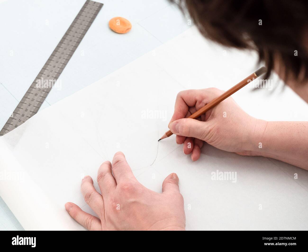 tailor copies pattern layout of dress with pencil and ruler on tracing ...