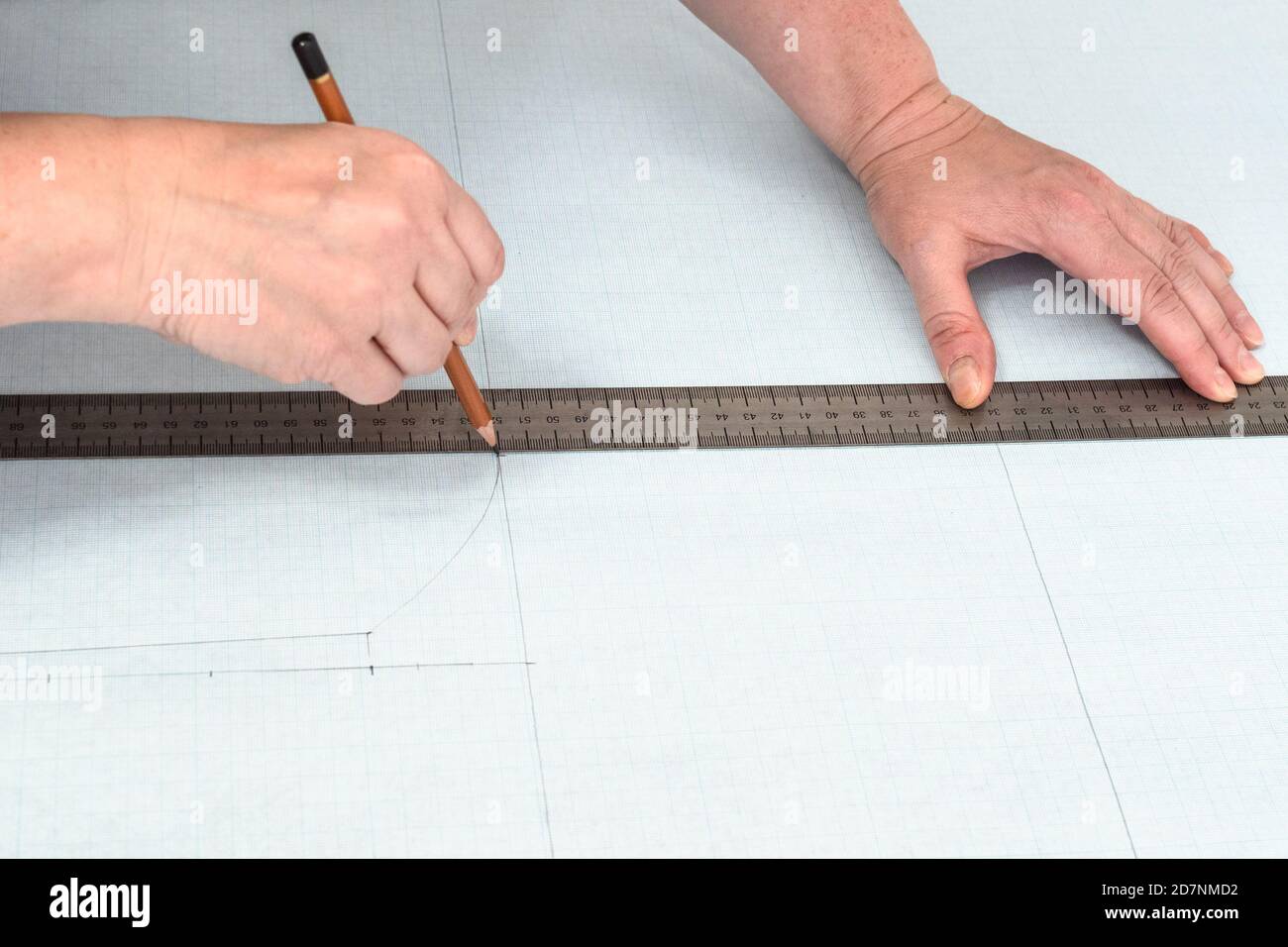 tailor's hands draw pattern layout of dress with pencil and ruler on ...