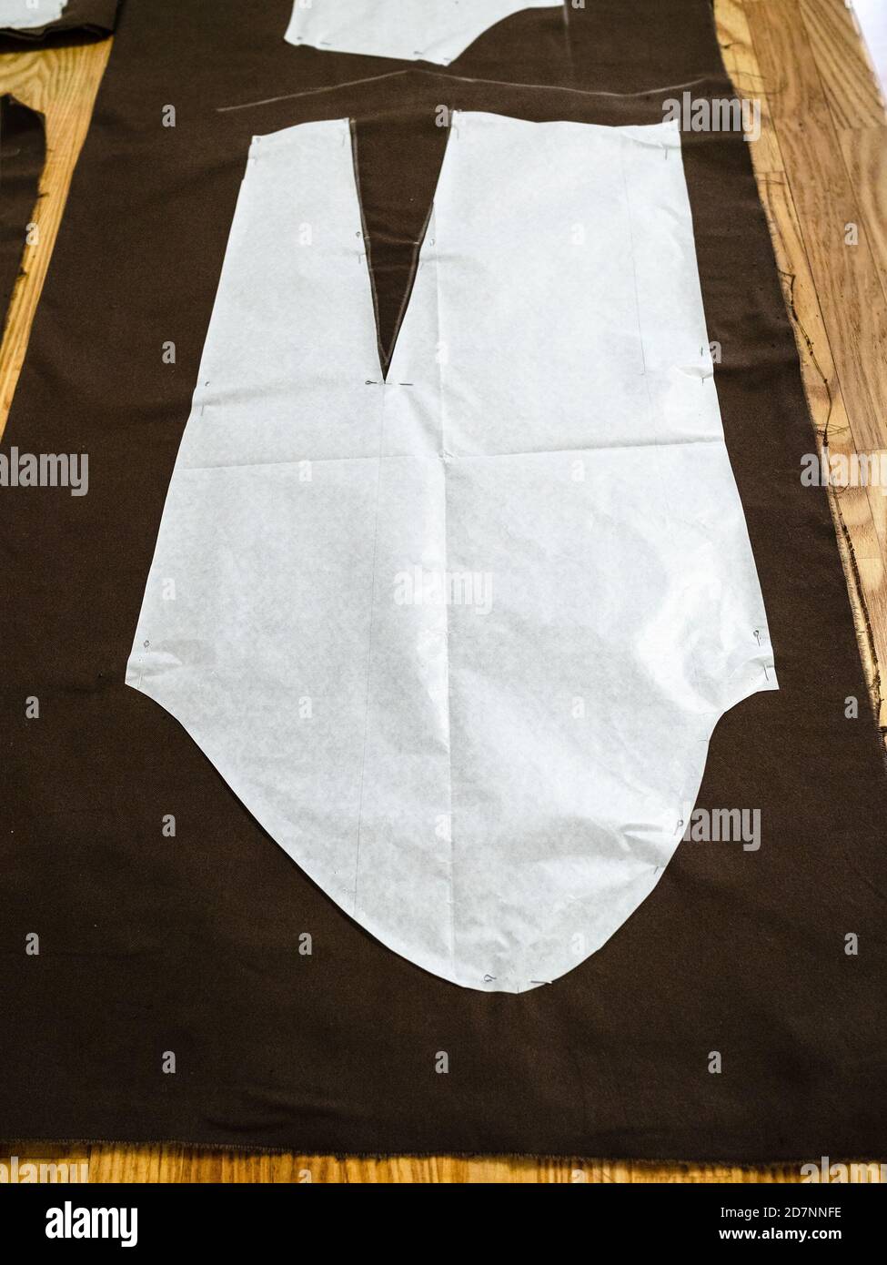 layout of sewing pattern of dress on brown fabric on wooden table at ...