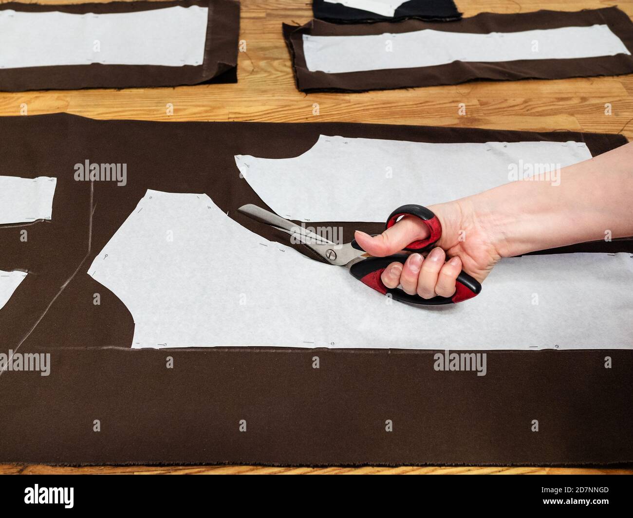 hand cuts brown fabric by scissors according with pattern layouts of ...