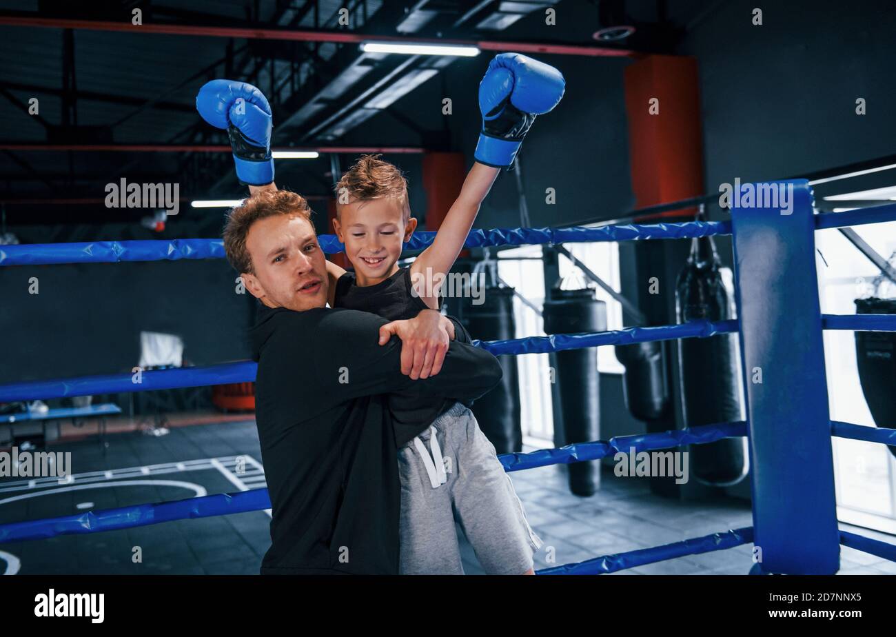 Boxing coach standing in the ring with boy and celebrating victory ...