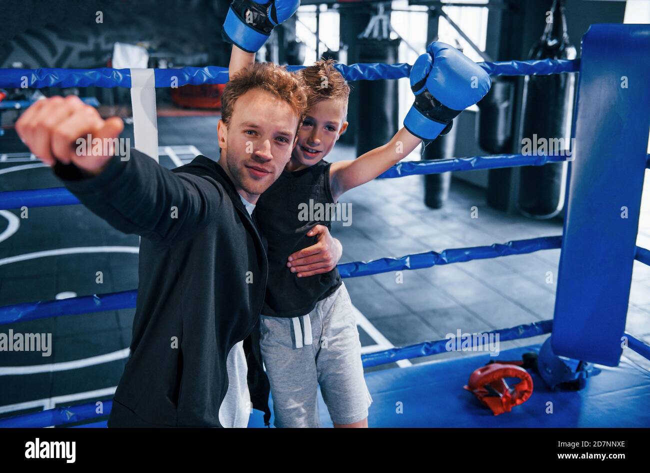 Boxing coach standing in the ring with boy and celebrating victory ...