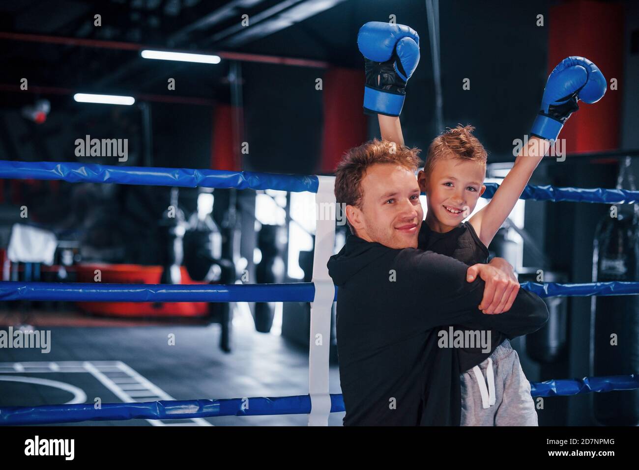 Boxing coach standing in the ring with boy and celebrating victory ...