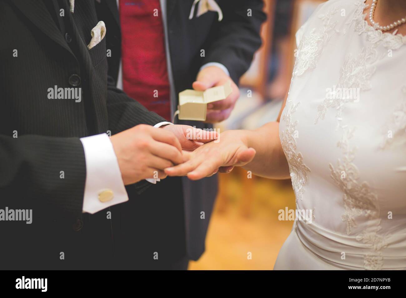 Groom putting wedding ring on bride's finger Stock Photo - Alamy
