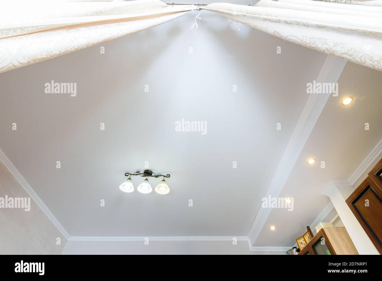 Two-level ceiling with a small chandelier in the interior of the room ...